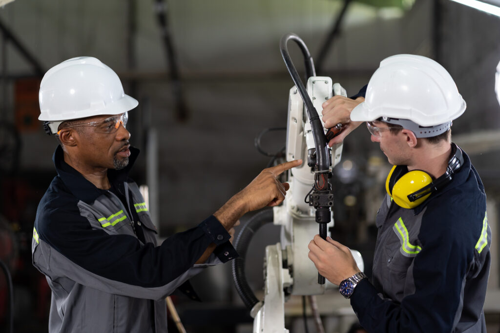 Group of male engineer worker maintenance automatic robotic arm machine in factory. Male ...